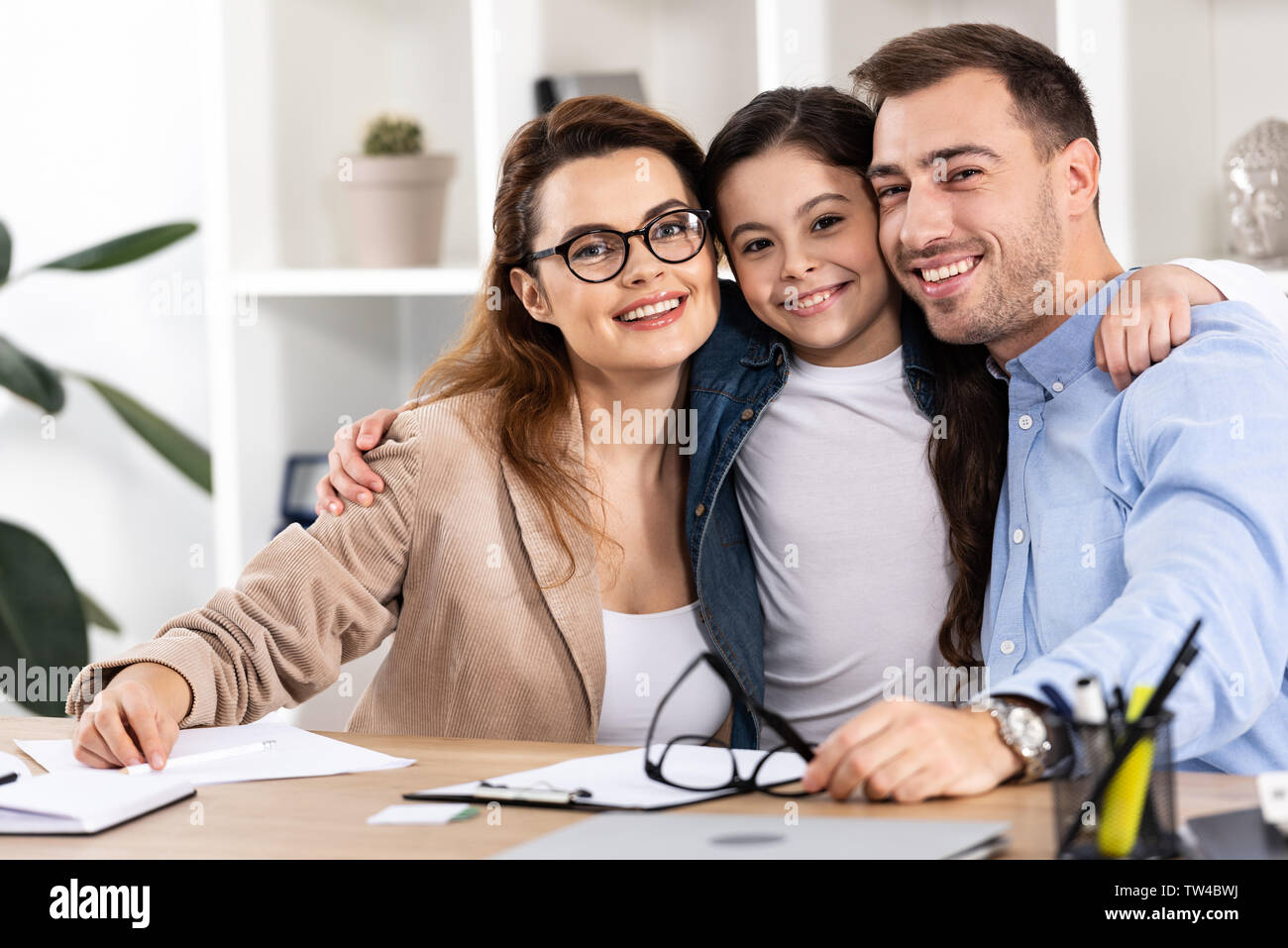 cheerful and cute kid hugging happy parents in office Stock Photo - Alamy