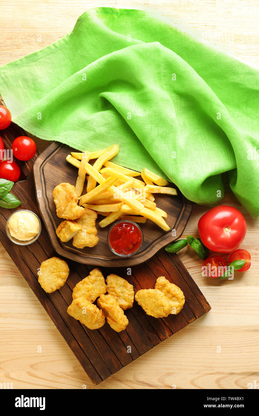 Tasty nuggets, french fries and small bowls with sauces for chicken on ...
