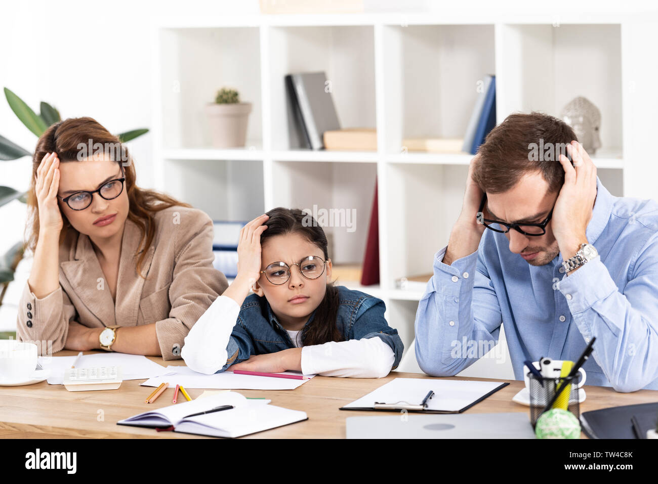 cute kid in glasses sitting with exhausted parents in office Stock ...