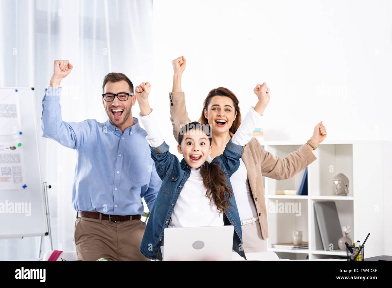 cheerful family celebrating triumph near laptop in office Stock Photo ...