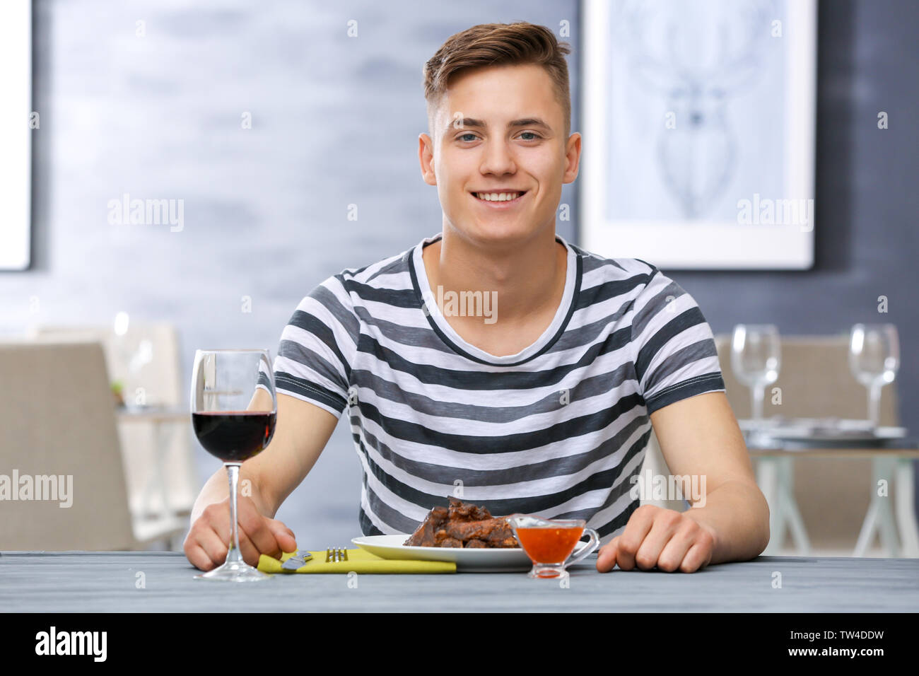 Young man eating delicious ribs in restaurant Stock Photo - Alamy