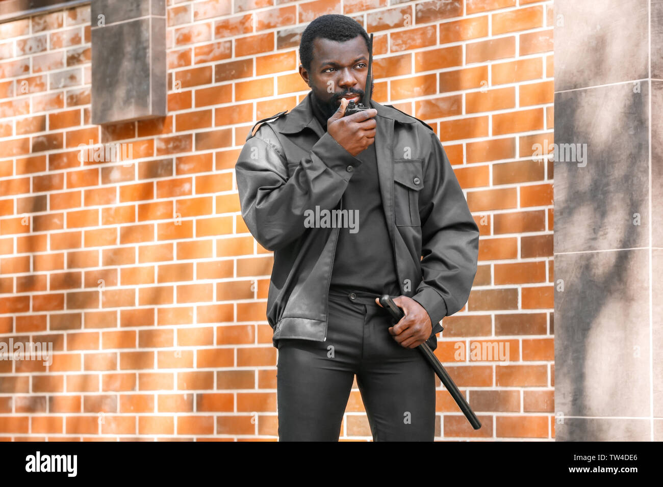 Security guard using portable radio outdoors Stock Photo - Alamy