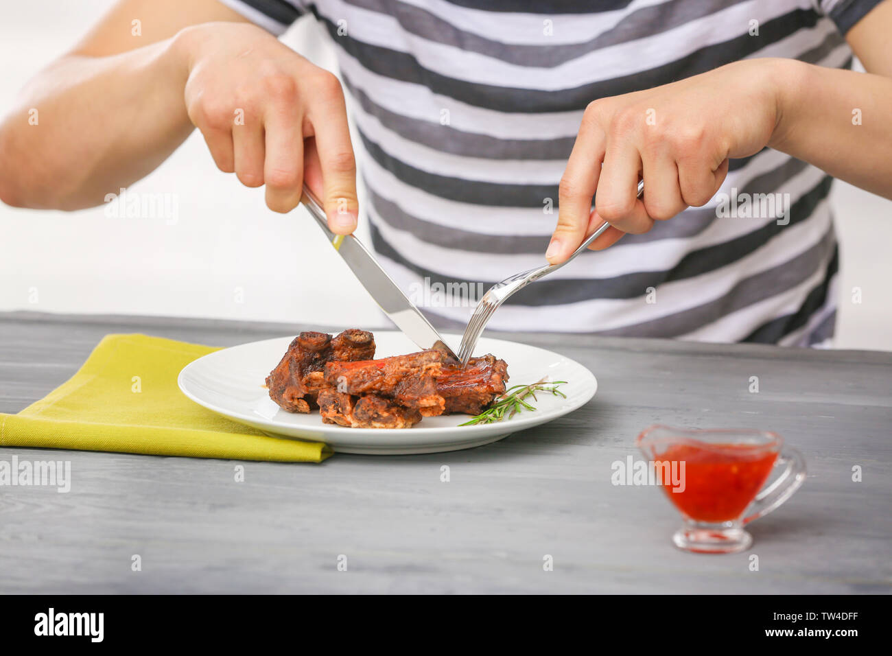 Young man eating delicious ribs in restaurant Stock Photo - Alamy