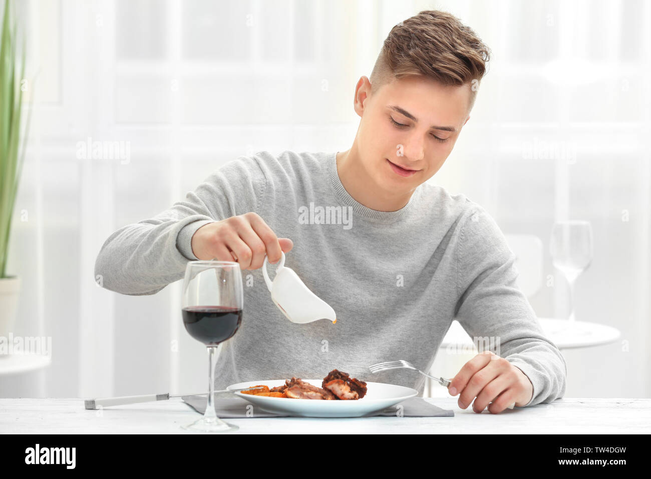 Young man eating delicious ribs in restaurant Stock Photo - Alamy