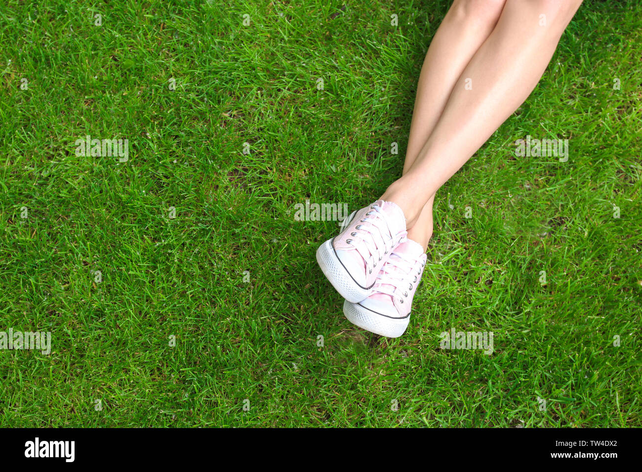 Beautiful female legs on green grass background Stock Photo - Alamy
