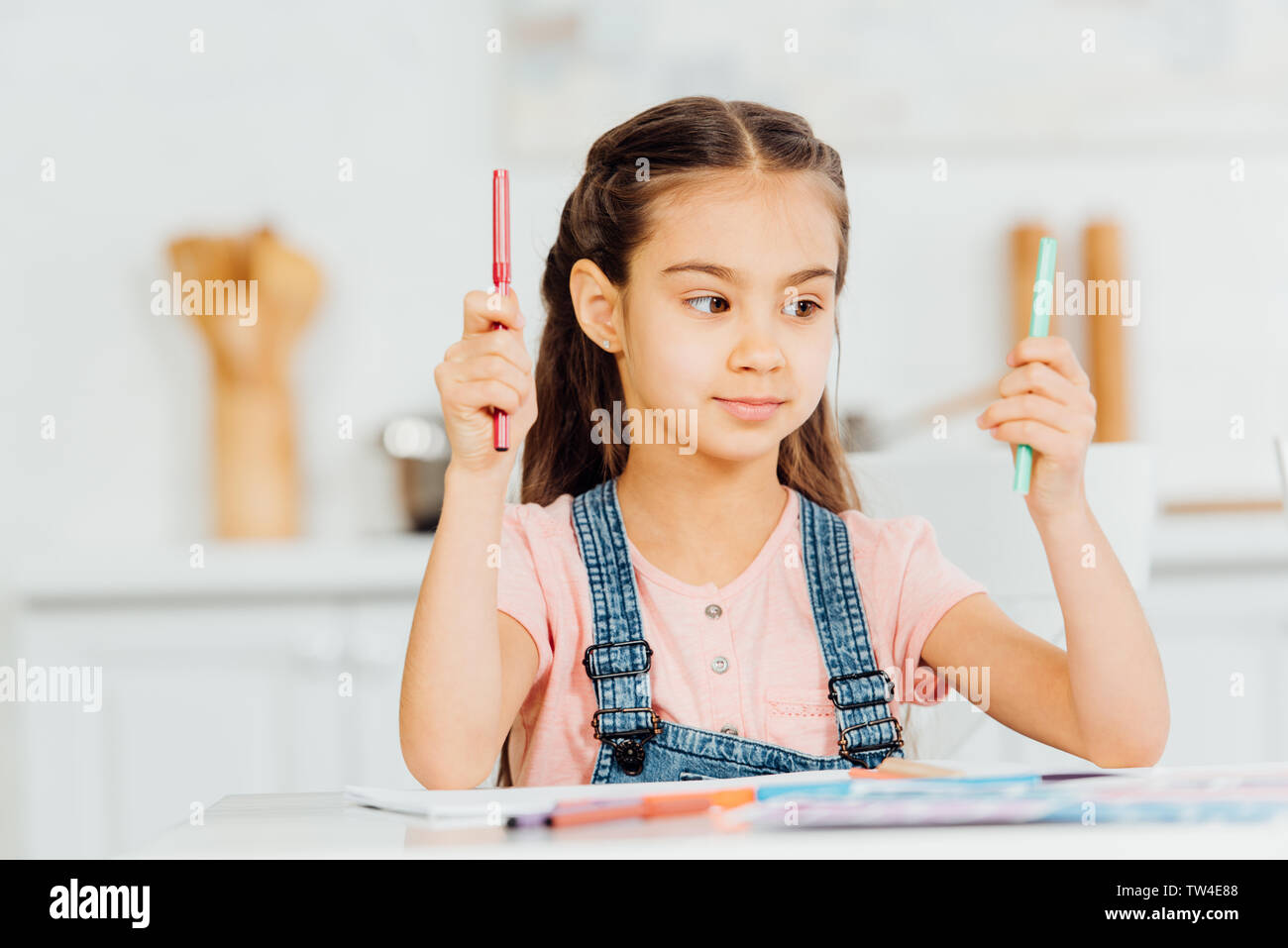 cute kid choosing between turquoise and red felt pens at home Stock ...