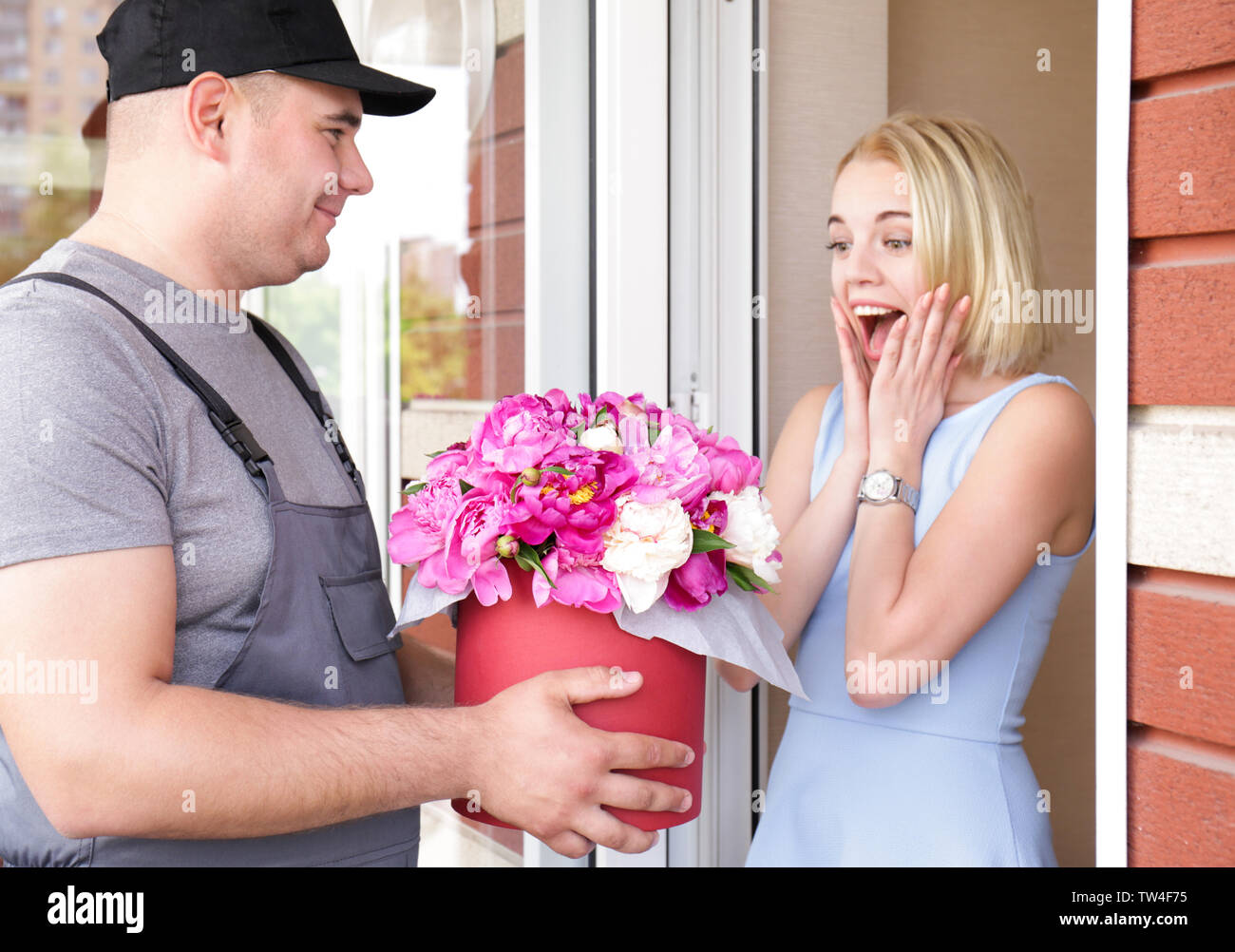 Young woman receiving beautiful peony flowers from delivery man Stock ...