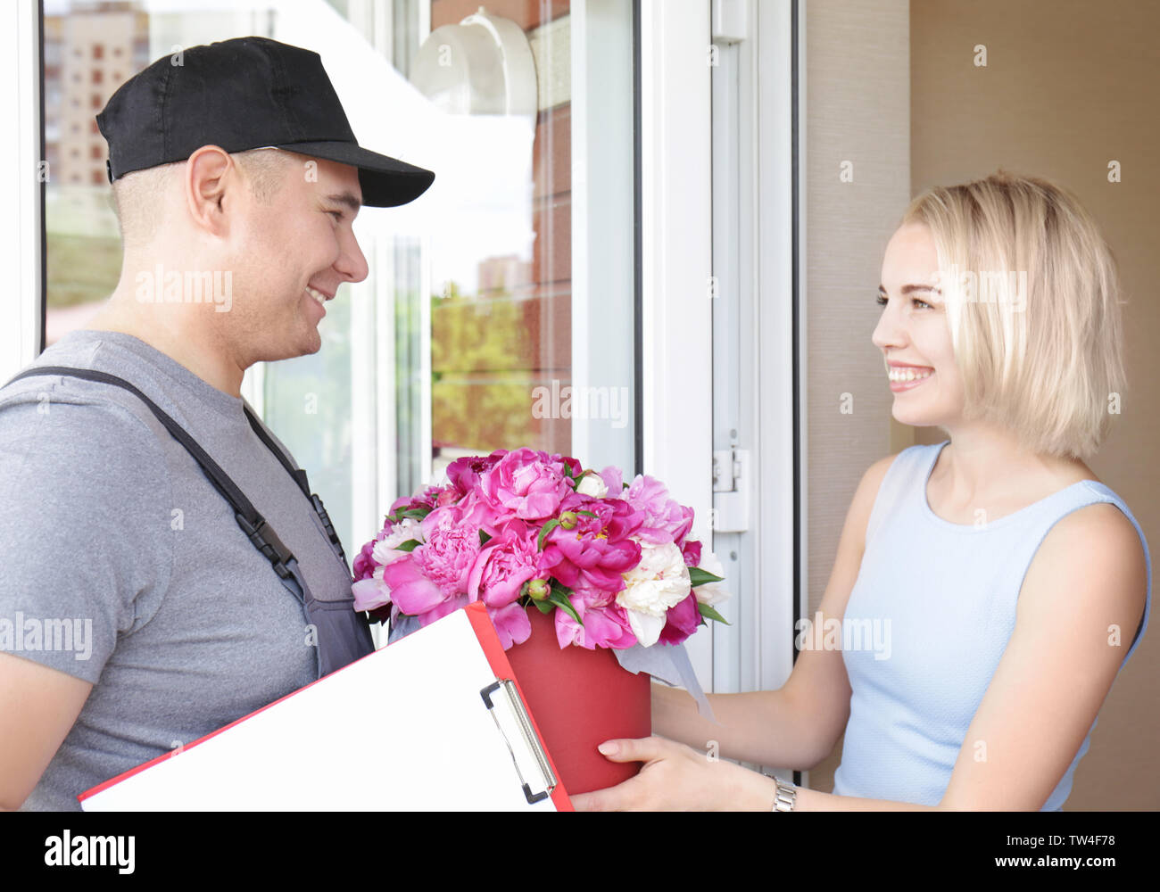 Young woman receiving beautiful peony flowers from delivery man Stock ...