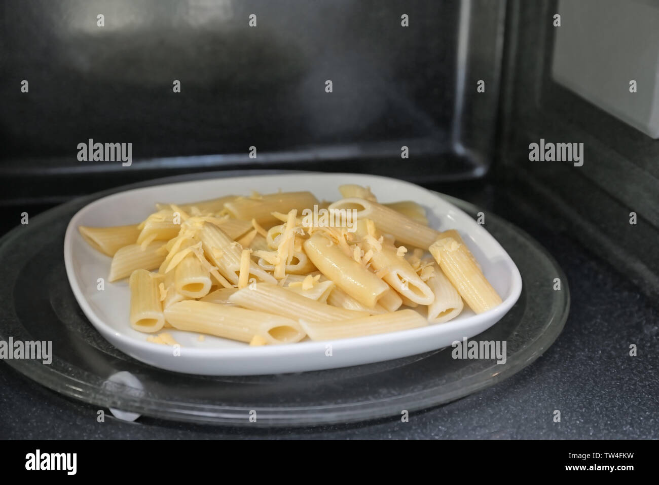 Plate of pasta with cheese in microwave Stock Photo - Alamy