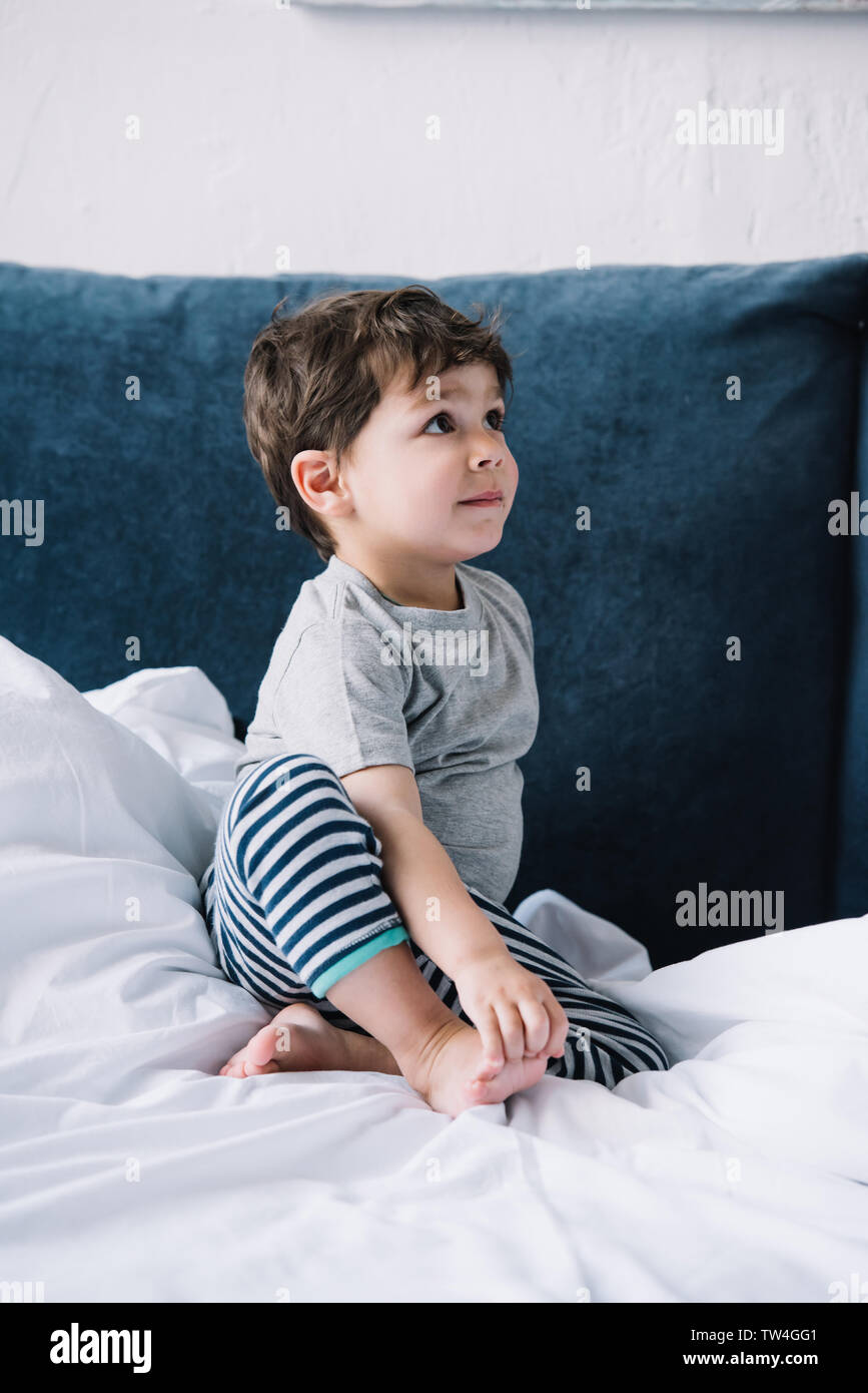 cute kid sitting on bed with white bedding at home Stock Photo - Alamy