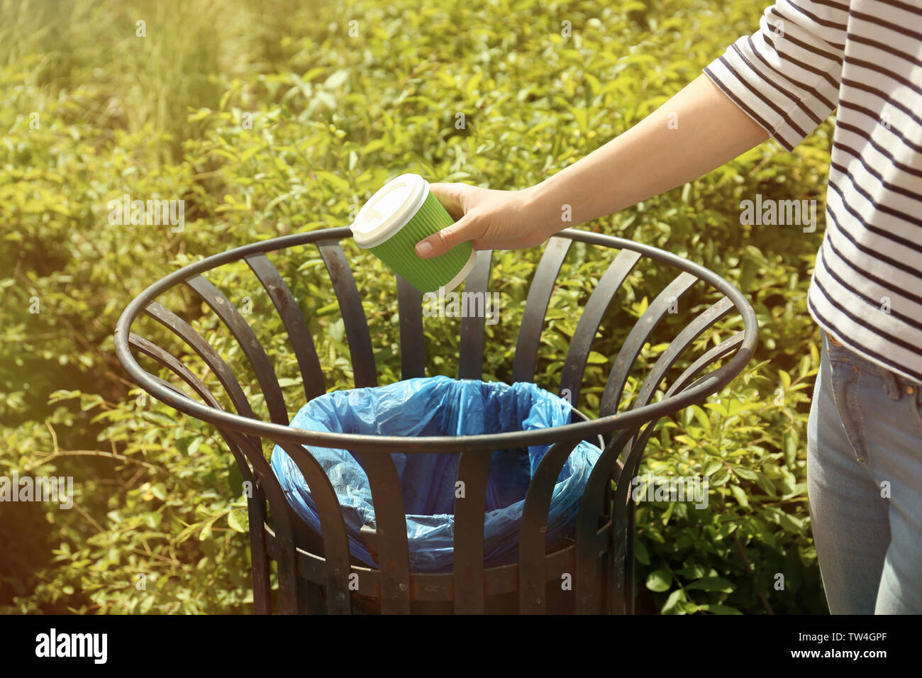 Young woman throwing paper cup in litter bin outdoors Stock Photo - Alamy