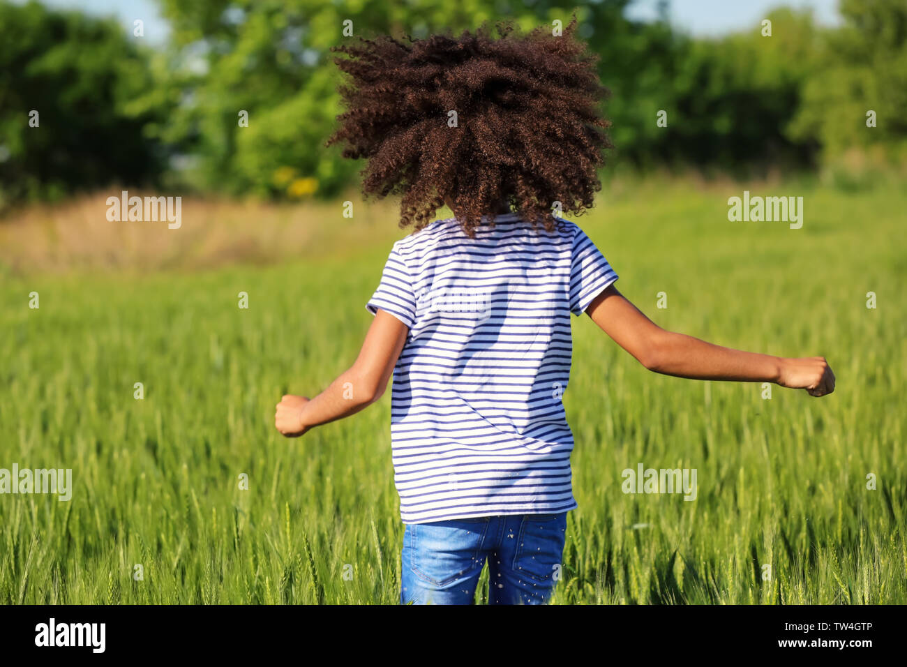 Little Afro American girl in green field Stock Photo - Alamy