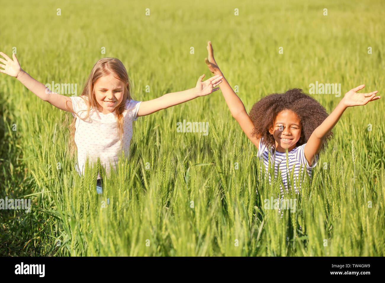 Happy little girls in green field Stock Photo - Alamy