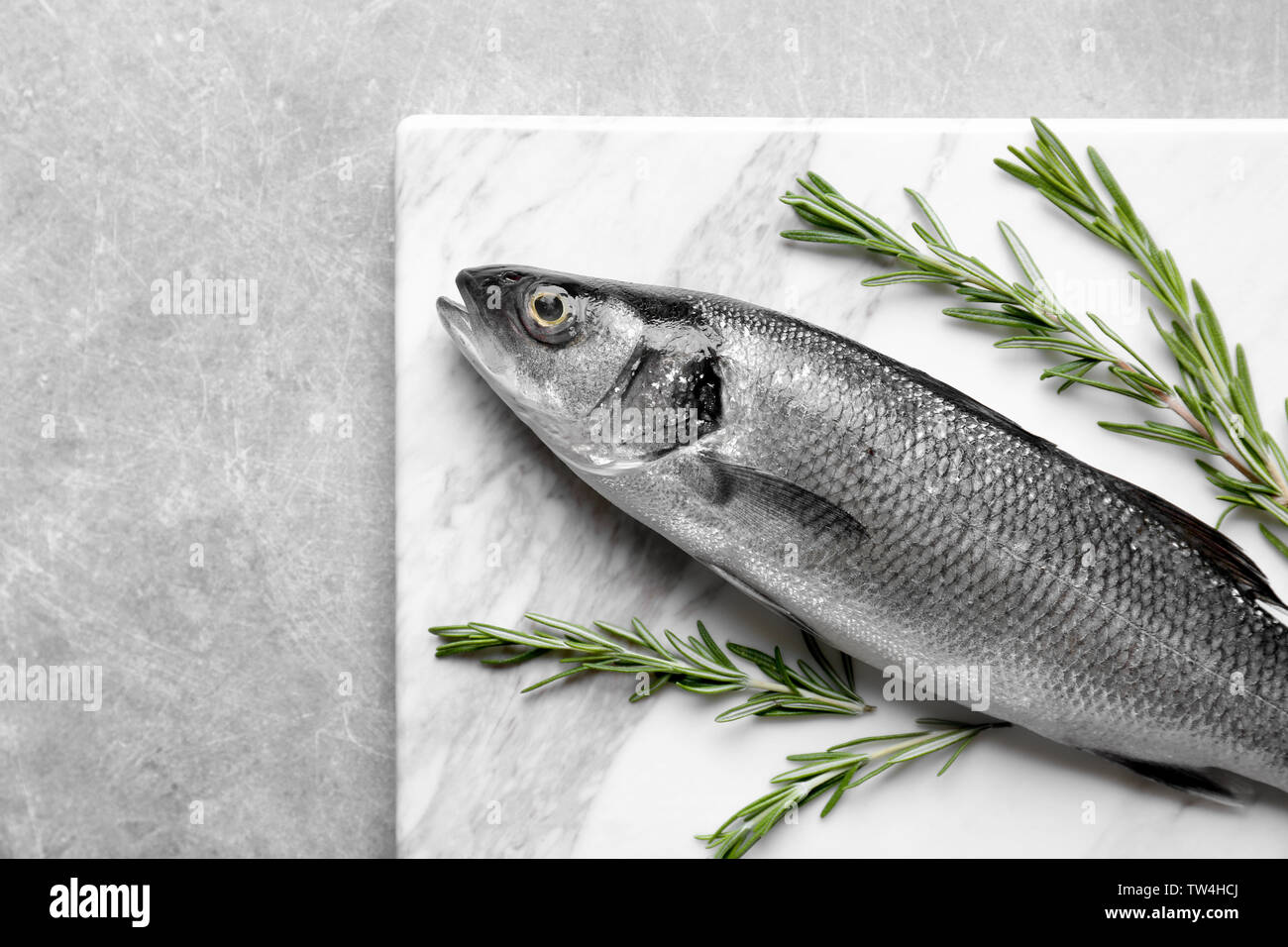Fresh fish with rosemary on gray background Stock Photo - Alamy