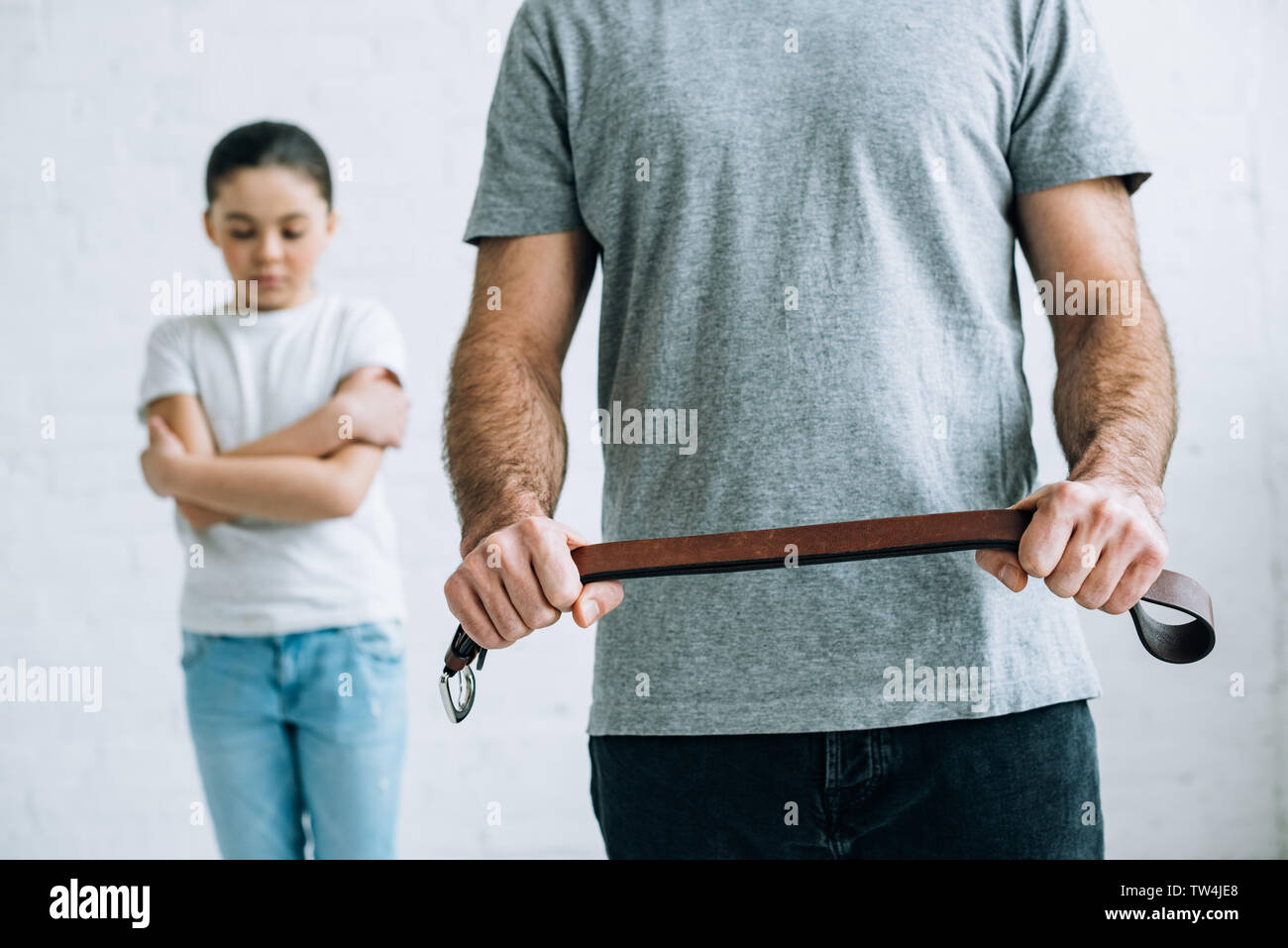 cropped view of father holding belt and upset daughter at home Stock ...