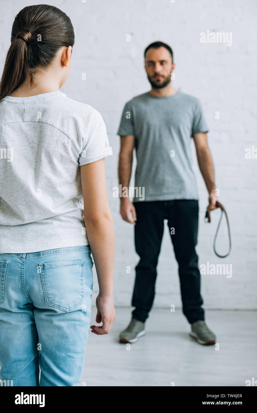 back view of daughter looking at father with belt in hand Stock Photo ...