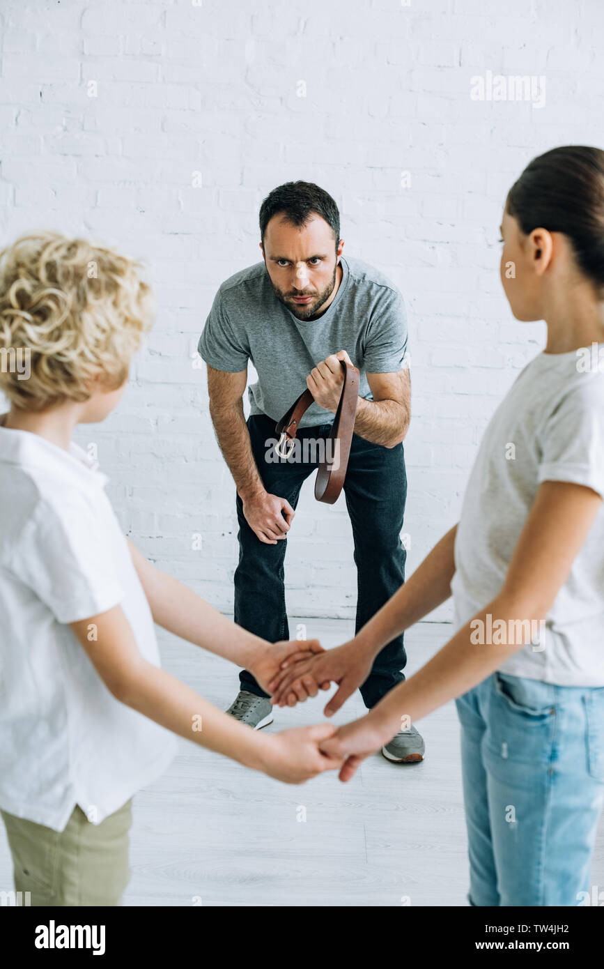 abusive father holding belt and children holding hands at home Stock ...