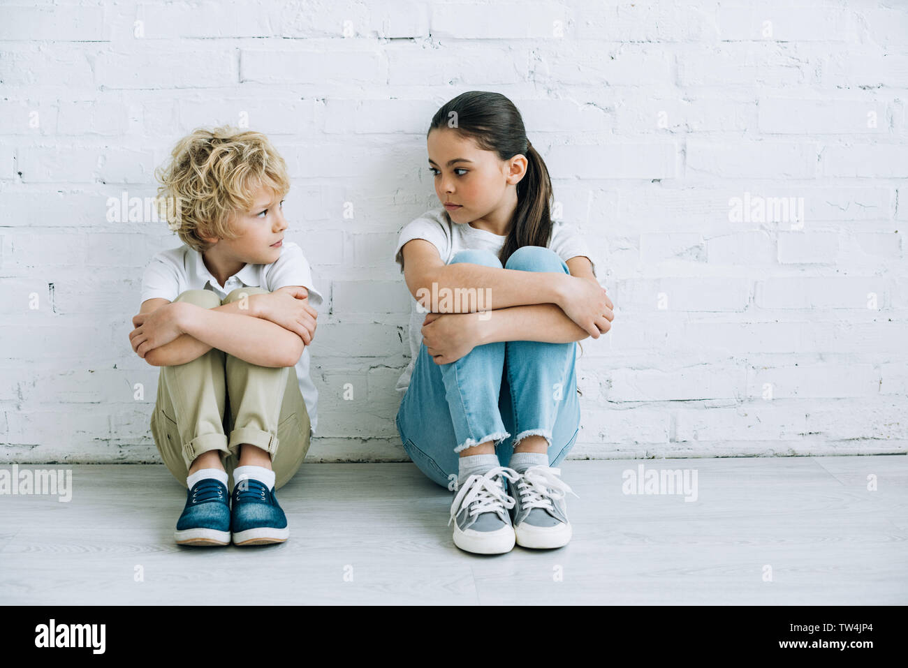 upset sister and brother sitting on floor at home Stock Photo - Alamy