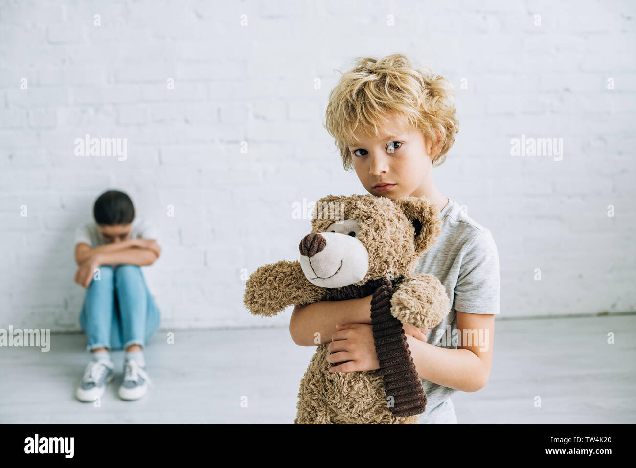 preteen boy holding teddy bear while his sister crying at home Stock ...