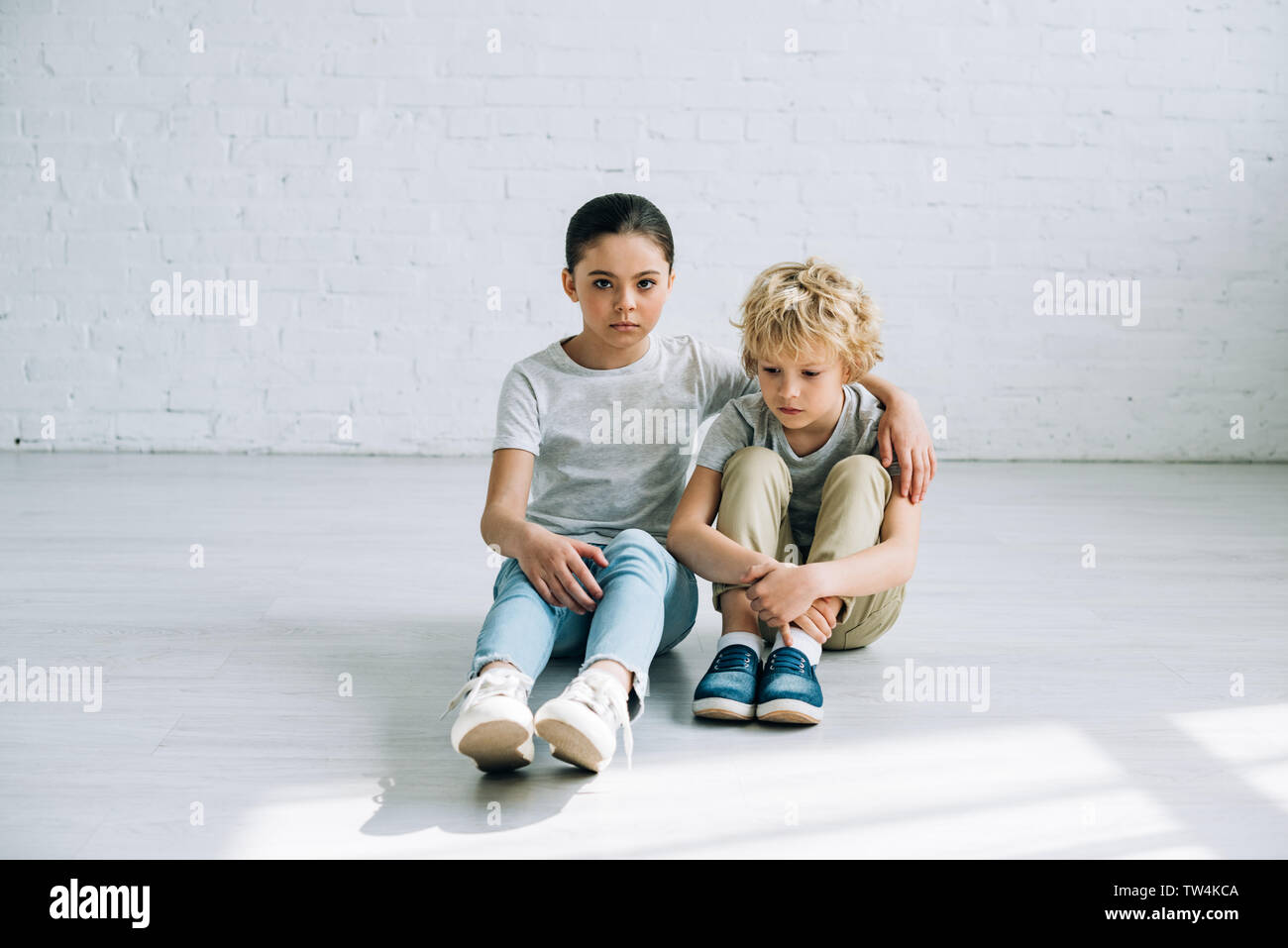 sad sister sitting on floor and embracing brother Stock Photo - Alamy