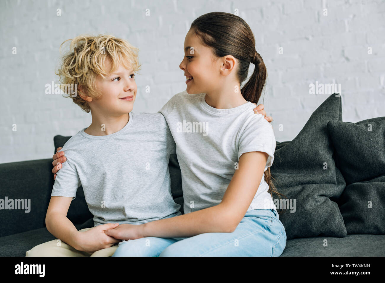 Smiling Brother And Sister Embracing And Looking At Each Other Stock