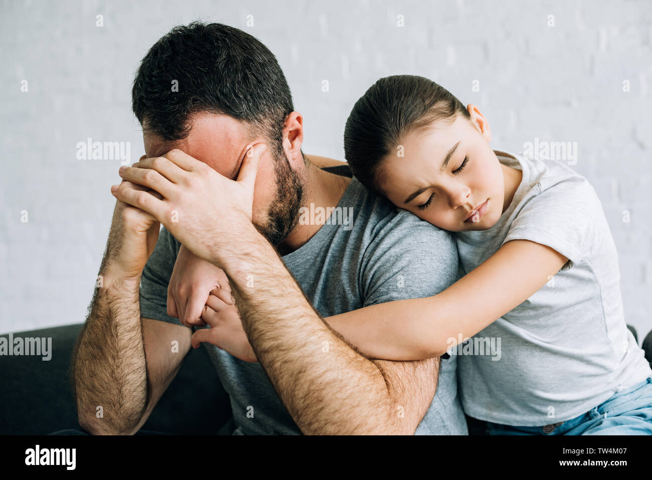 sad kid embracing stressed father in living room Stock Photo - Alamy