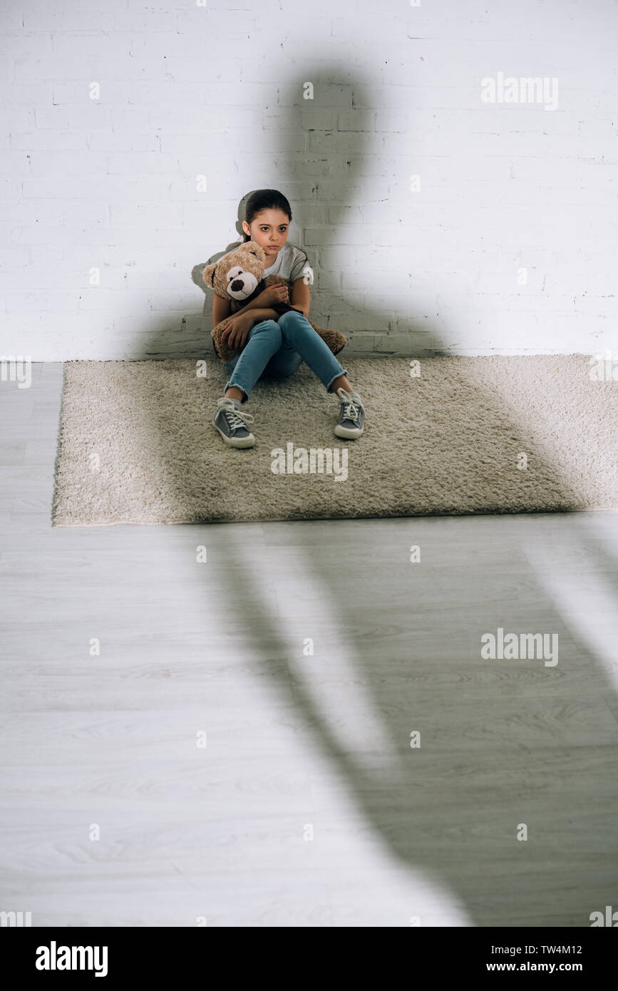 scared child with teddy bear sitting on carpet and big silhouette Stock ...