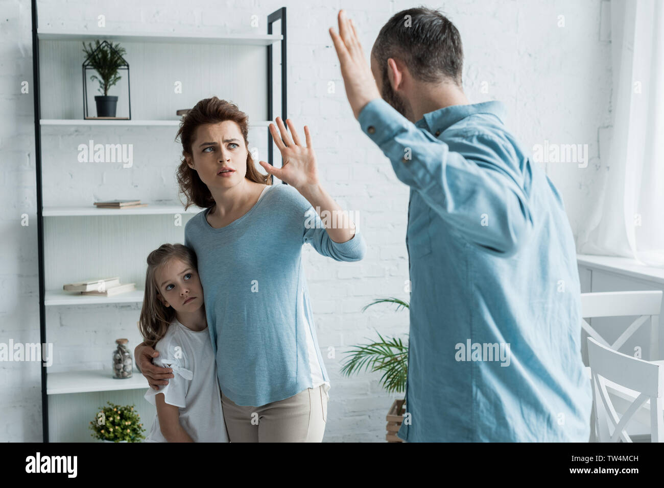 selective focus of scared mother gesturing while looking at angry ...