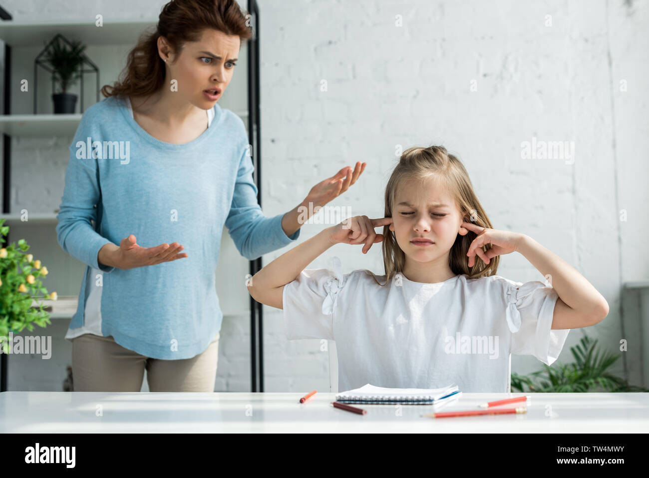 upset mother gesturing while talking near daughter with closed eyes ...
