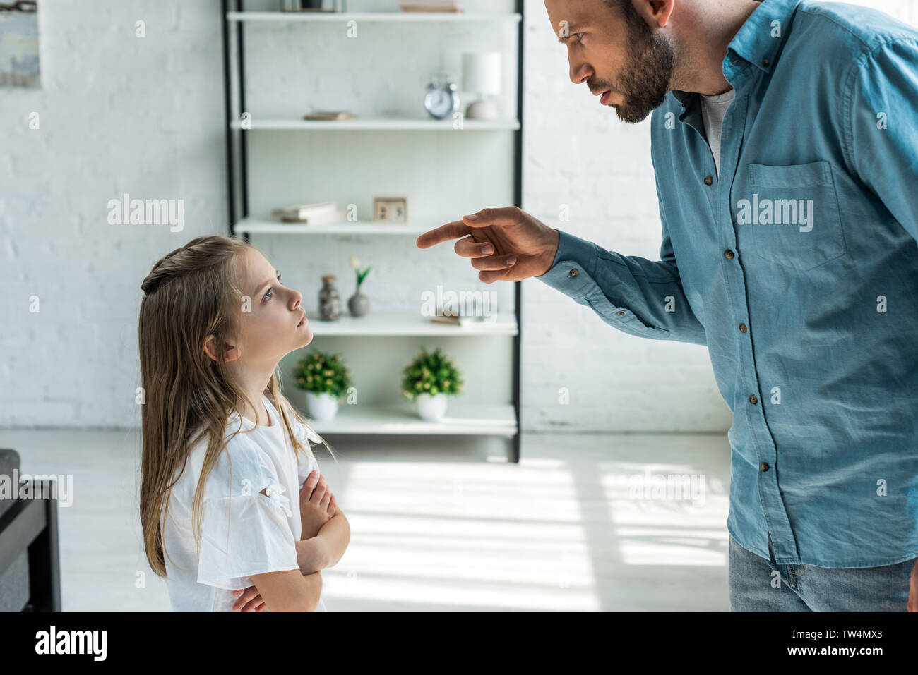 upset kid standing with crossed arms and looking at angry father Stock ...