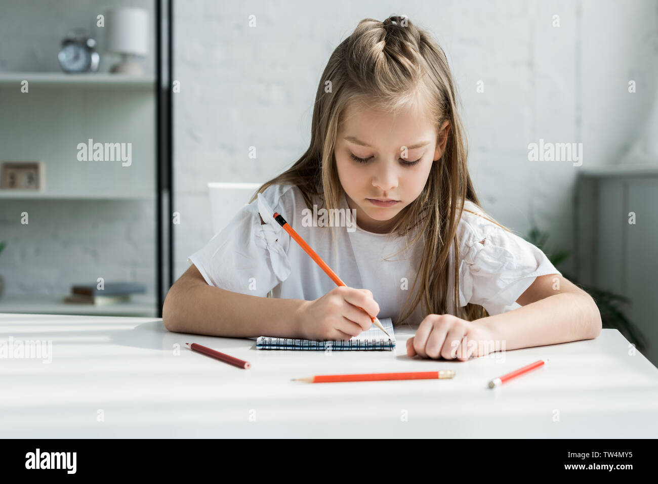 cute kid holding pencil while writing in notebook at home Stock Photo - Alamy