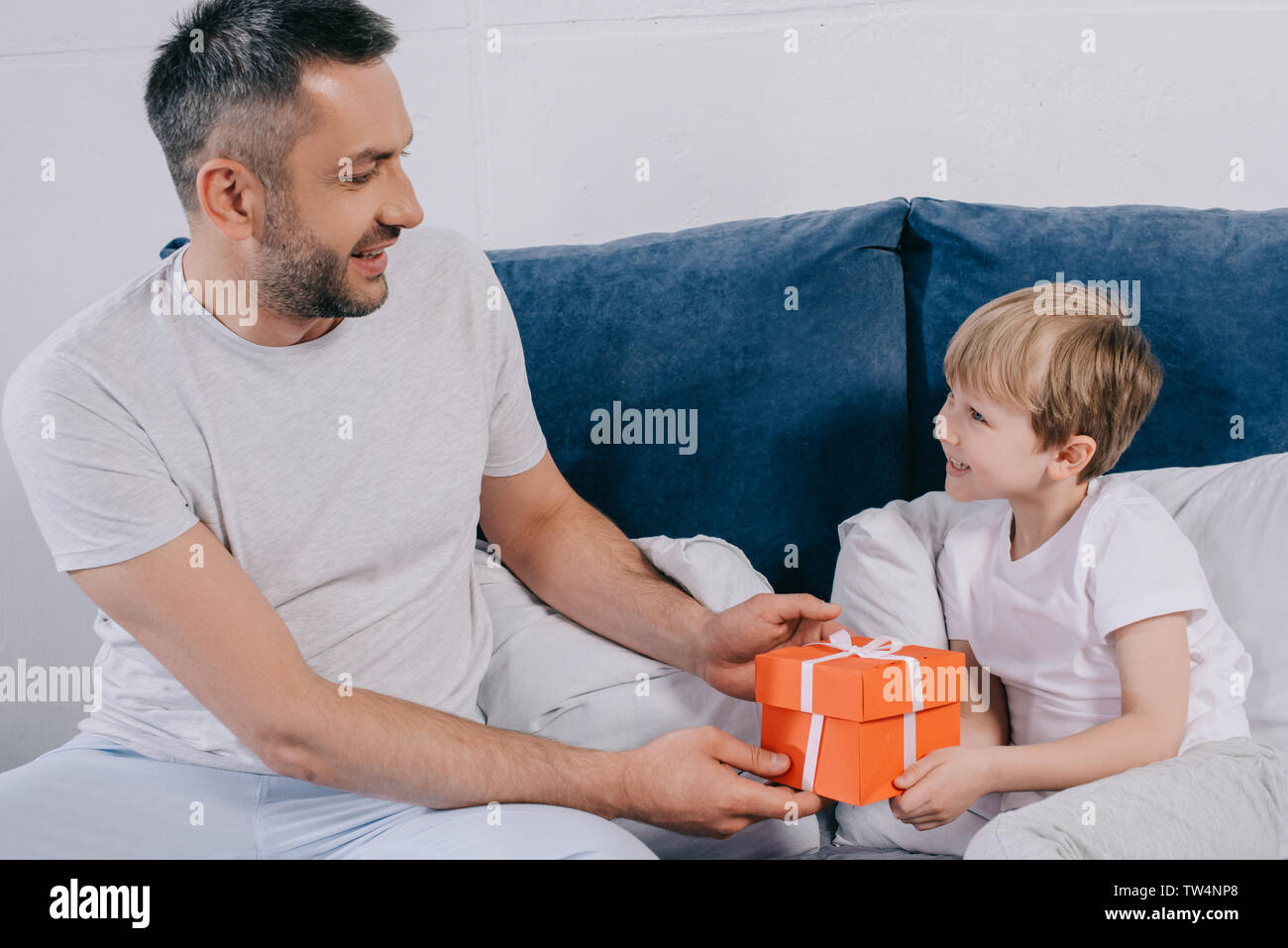 cute boy presenting gift box for fathers day to smiling daddy Stock ...