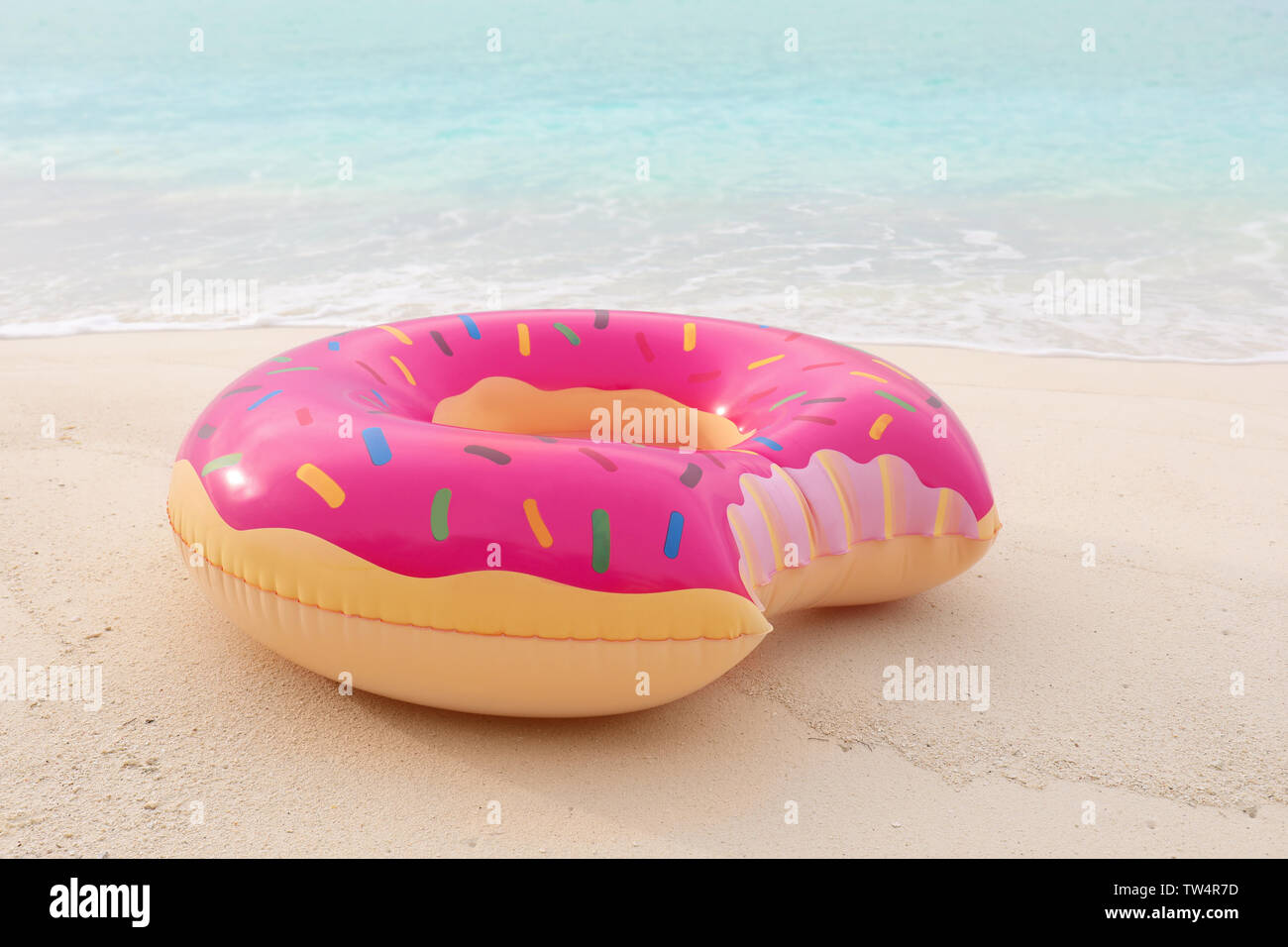 Colorful inflatable donut on sand at sea coast Stock Photo - Alamy