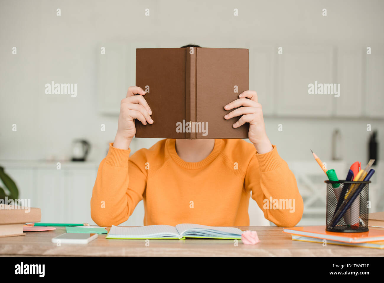 Boy hiding behind book hi-res stock photography and images - Alamy