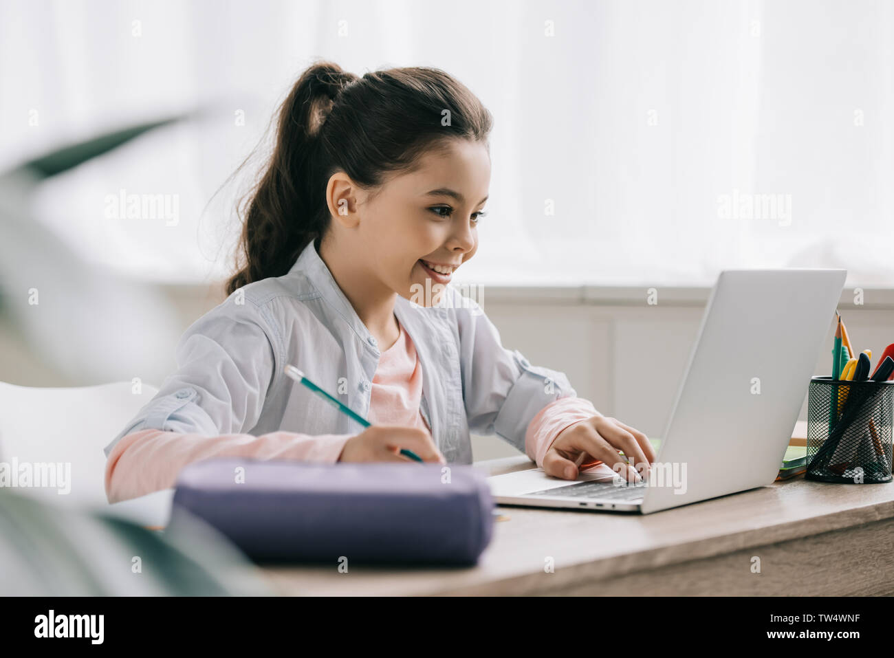 selective focus of cheerful child writing in notebook while doing ...