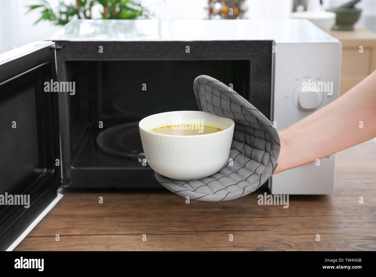 Woman taking bowl with delicious soup out of microwave in kitchen Stock ...