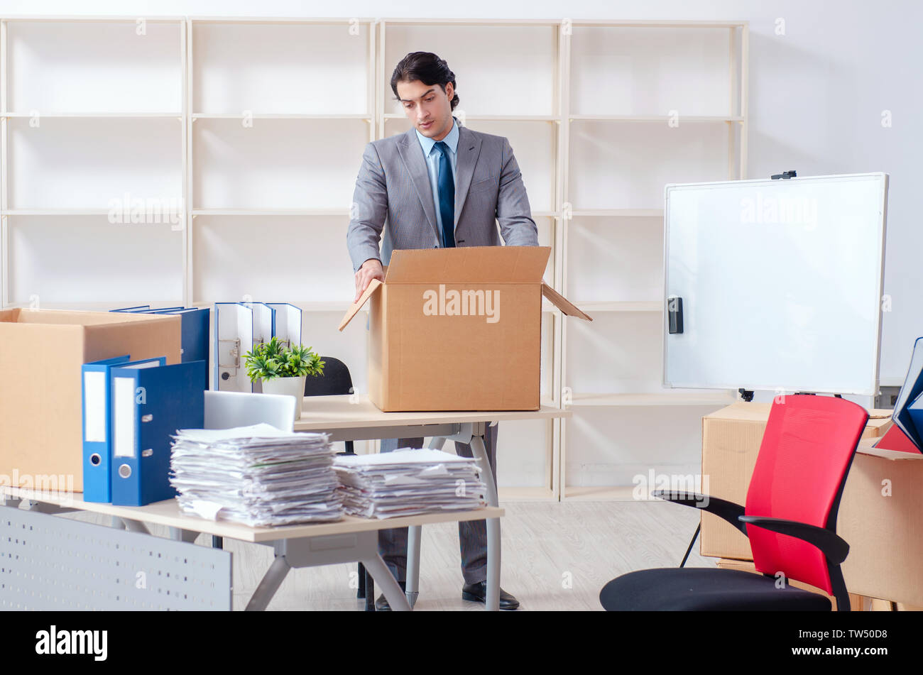 Young man employee with boxes in the office Stock Photo - Alamy
