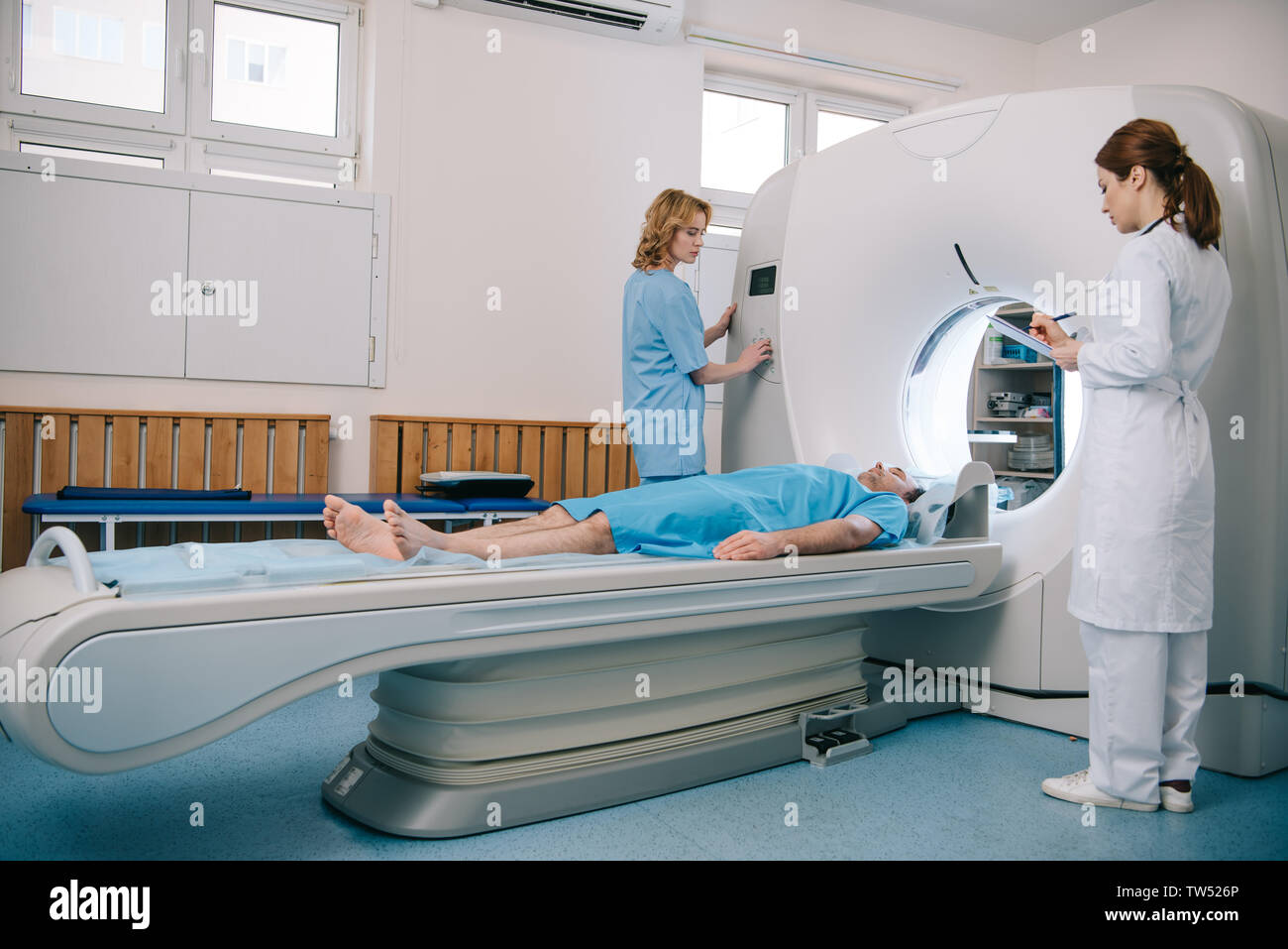 doctor writing on clipboard while standing by mri machine near ...