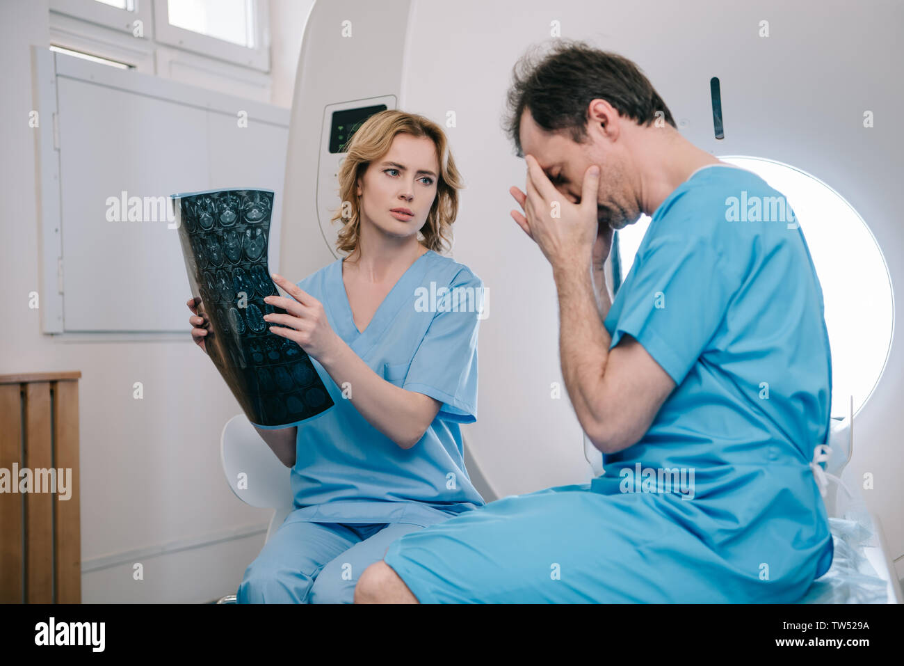upset patient covering face with hands while sitting near doctor ...