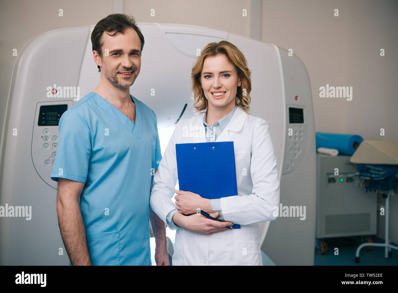 to smiling doctors looking at camera while standing near computed ...