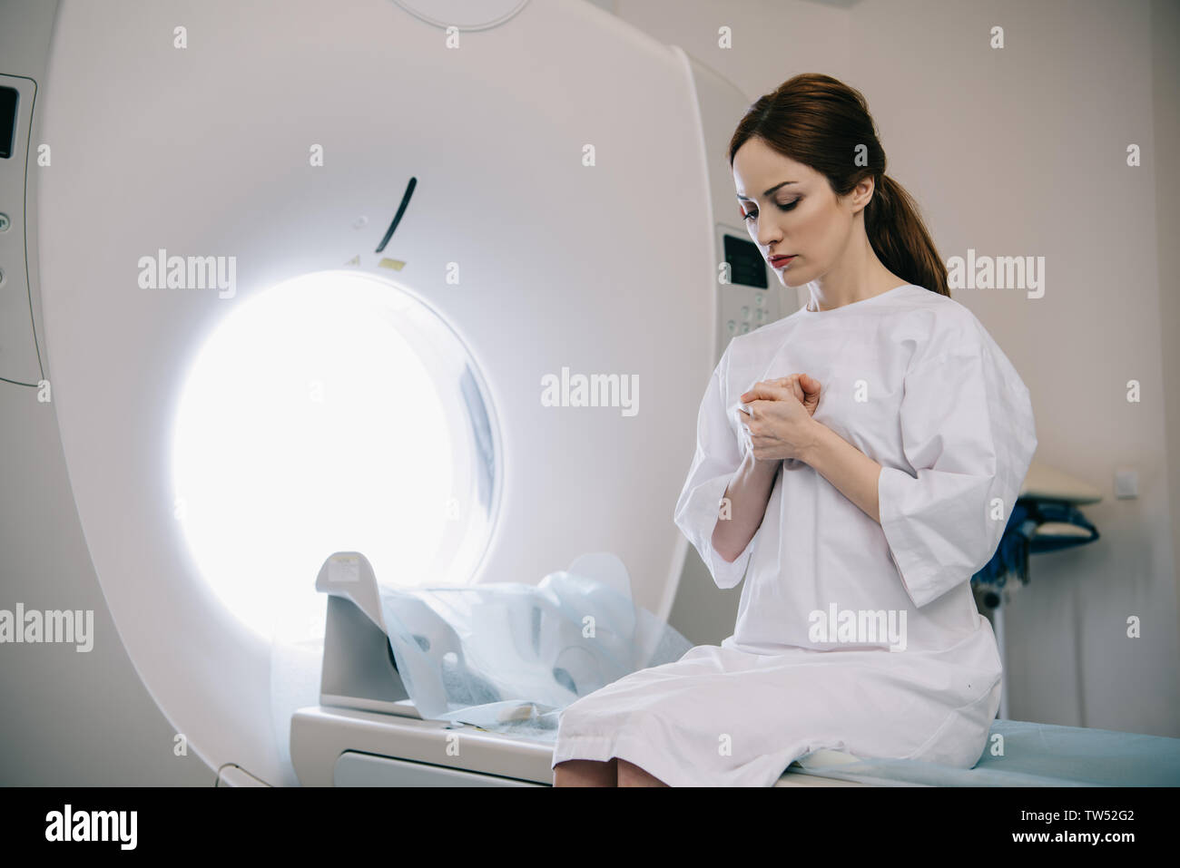 beautiful woman praying with closed eyes while sitting on mri scanner ...