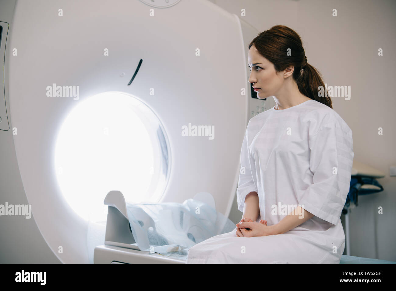 attractive woman sitting on computed tomography scanner bed in hospital ...