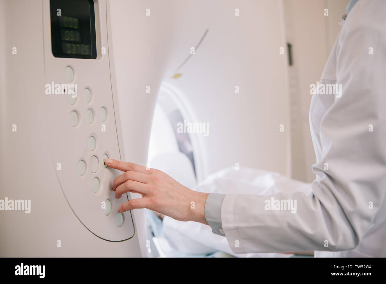cropped view of radiologist operating mri machine while patient lying ...
