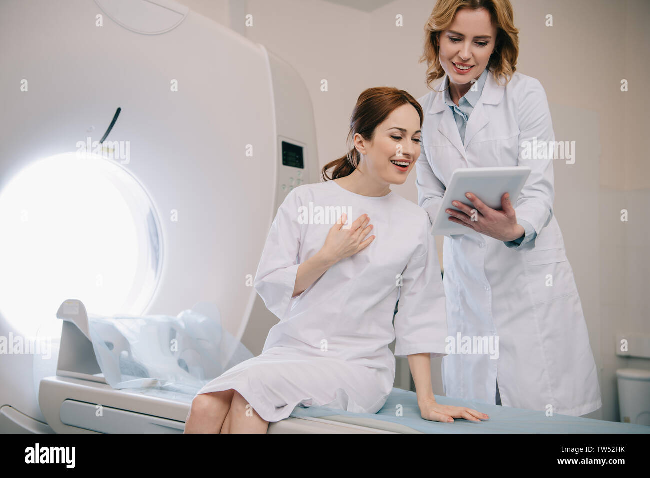 smiling radiologist showing x-ray diagnosis to happy patient sitting on ...