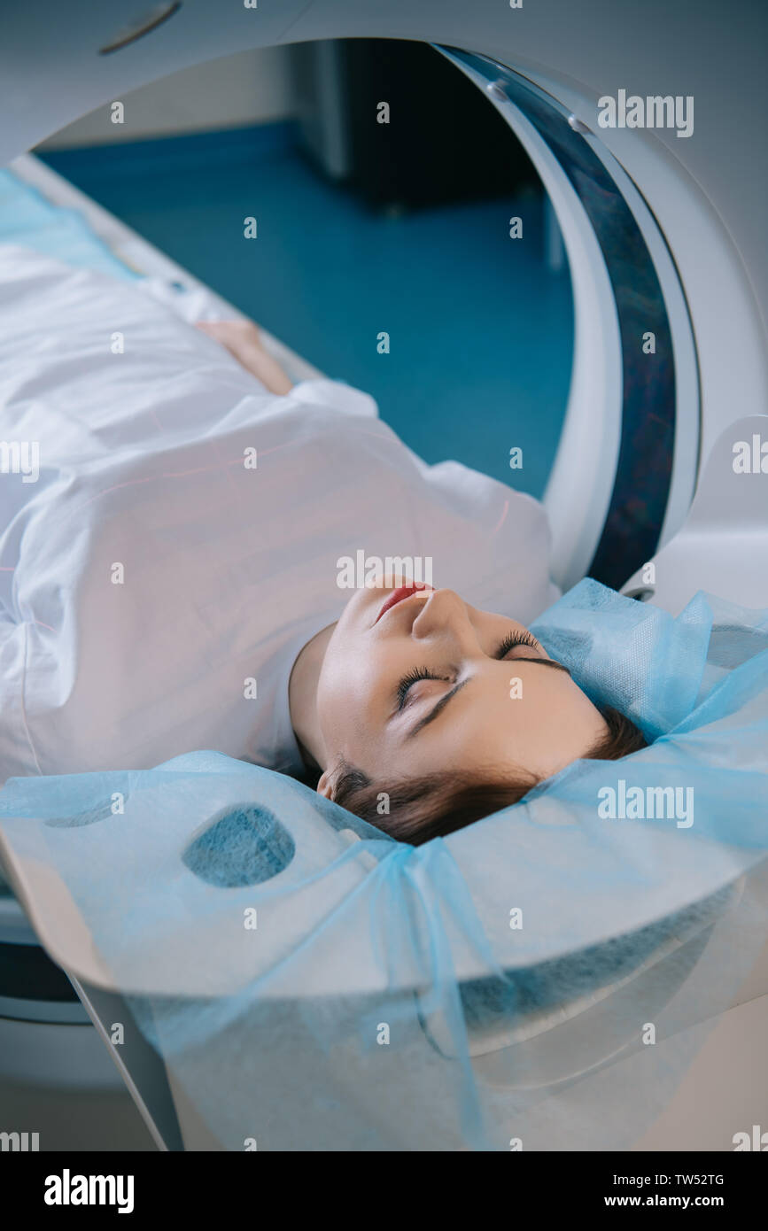 pretty woman lying with closed eyes on ct scanner bed during ...