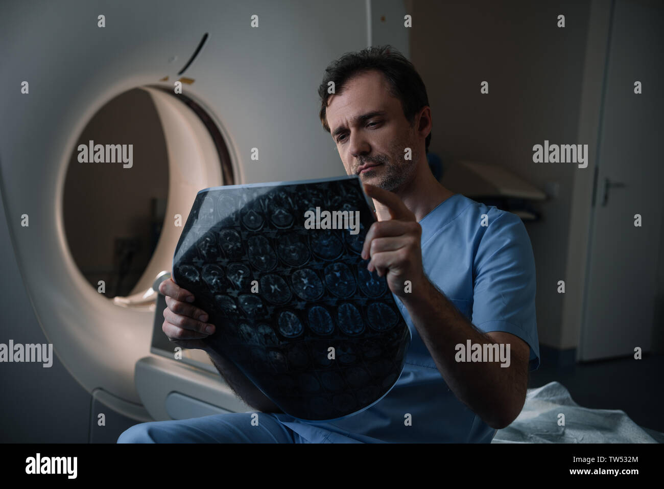 attentive doctor looking at tomography diagnosis while sitting near ct ...
