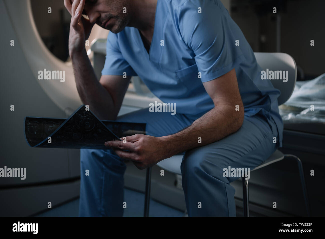 tired radiologist holding x-ray diagnosis while sitting near computed ...