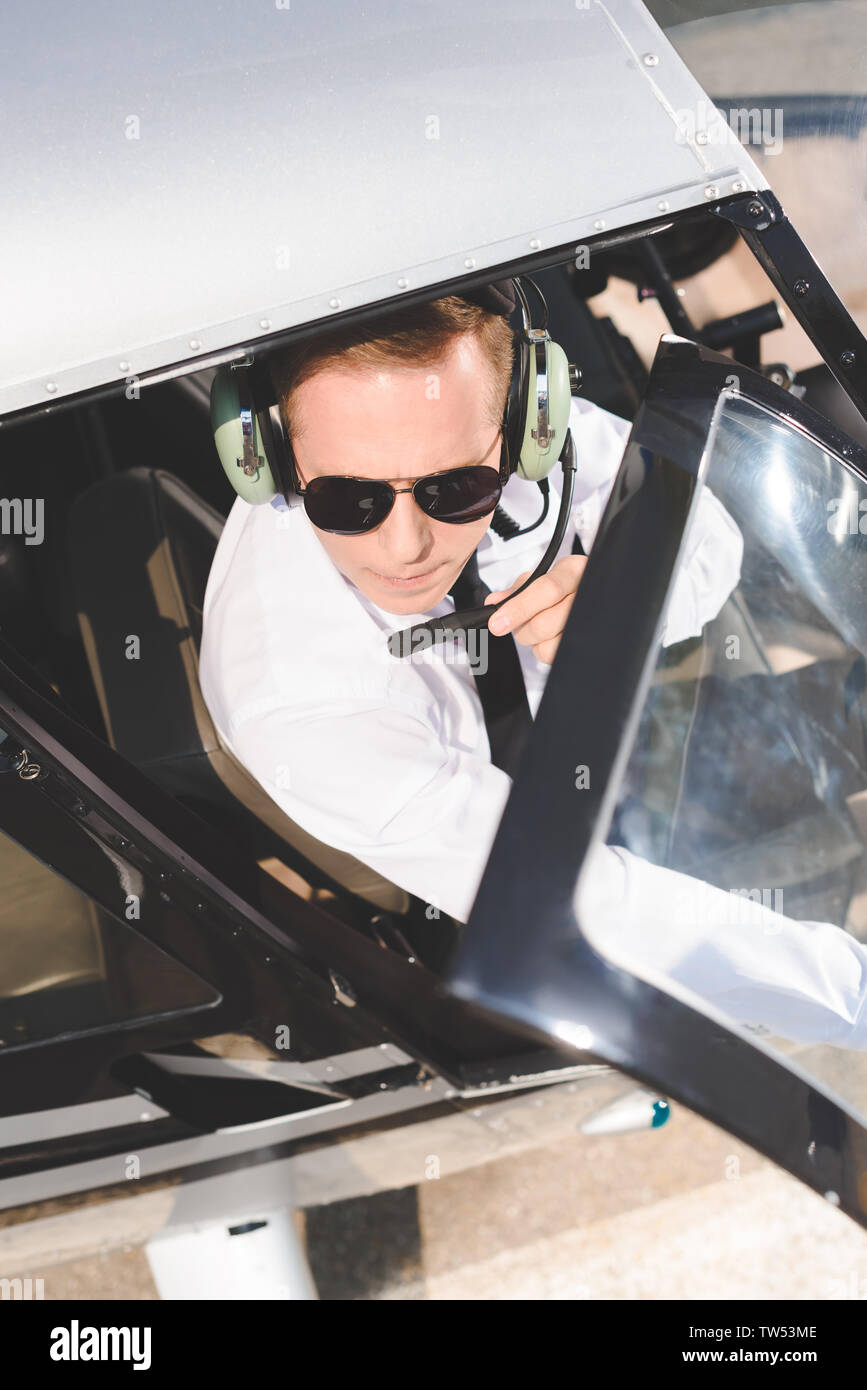 top view of Pilot in sunglasses and headset with microphone sitting in ...