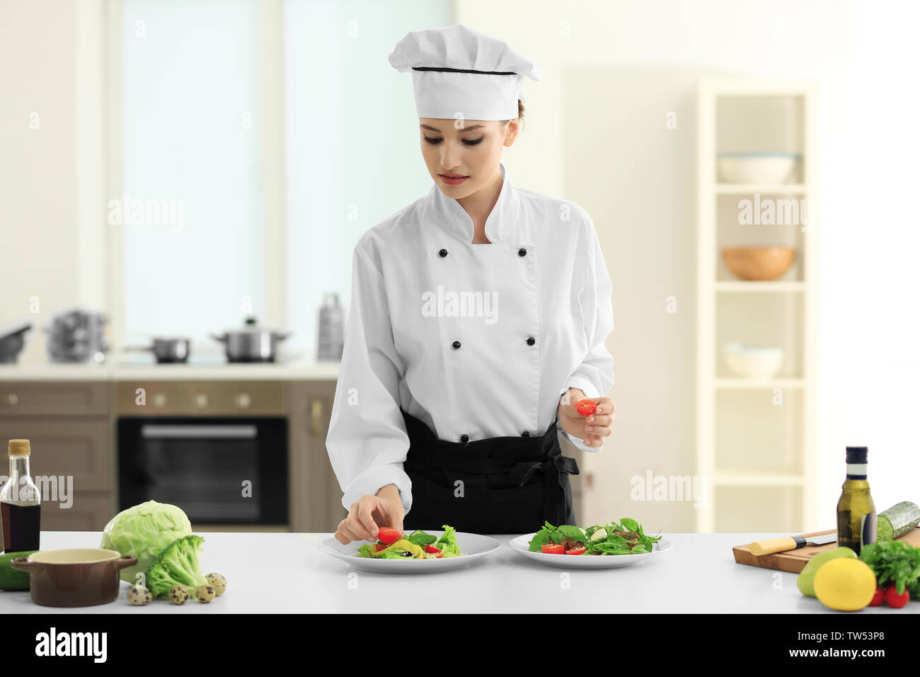 Young female chef with tasty dishes in kitchen Stock Photo - Alamy