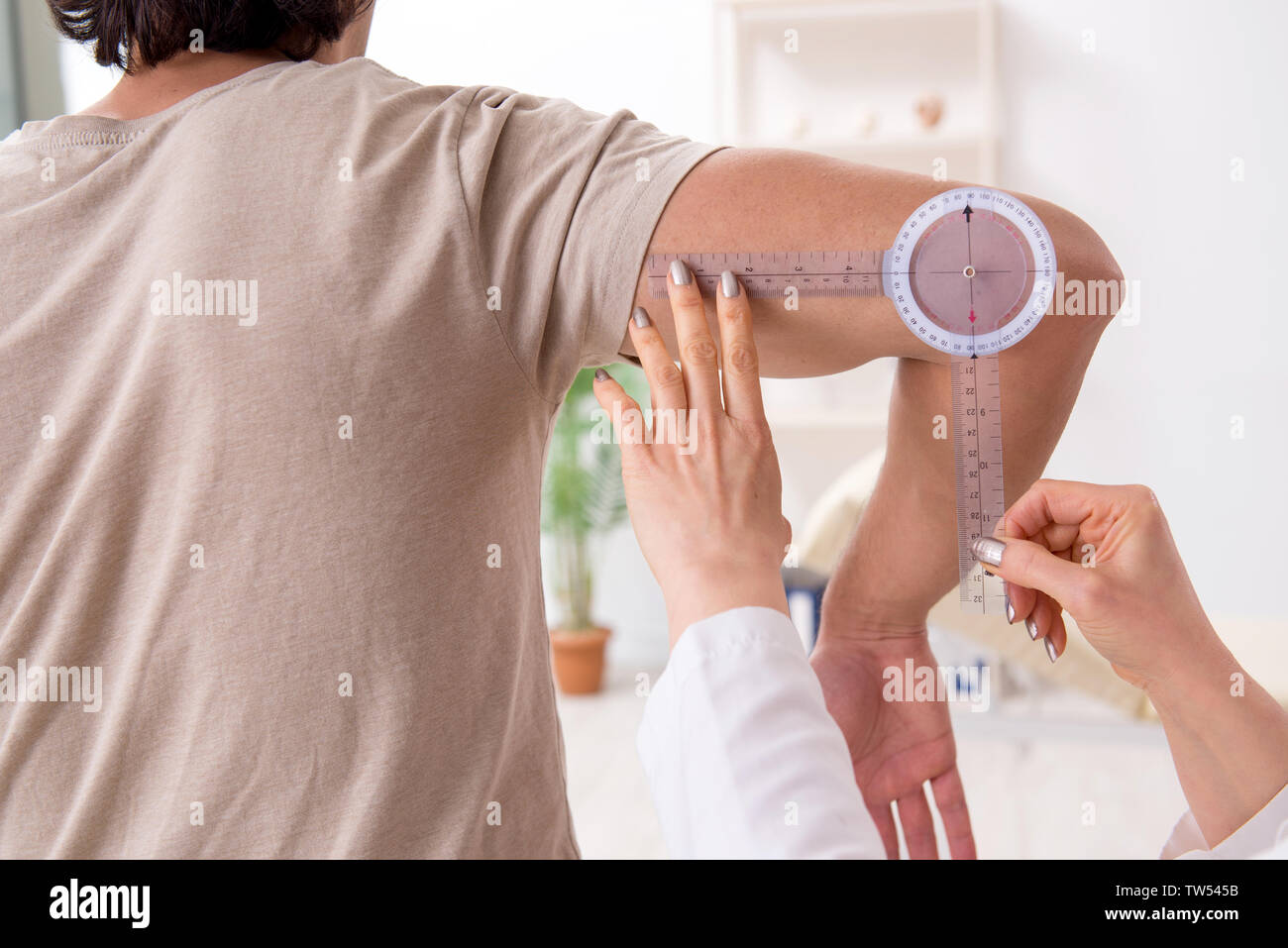 Female doctor checking patient's joint flexibility with goniometer ...